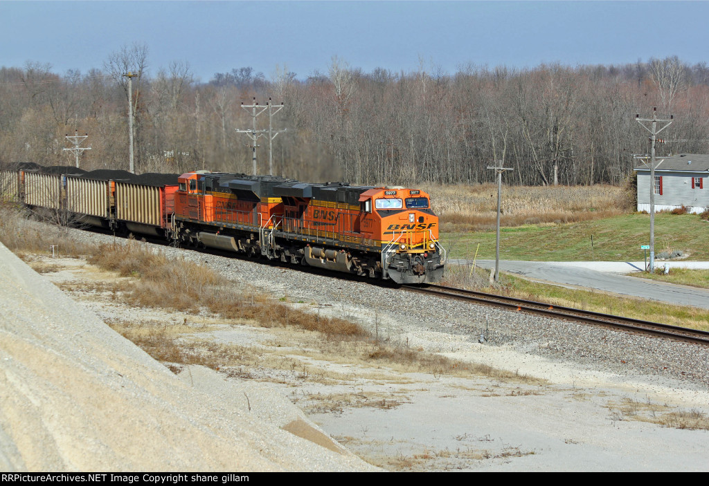 BNSF 5977 Heads Sb with a coal load On top a huge rock pile.
